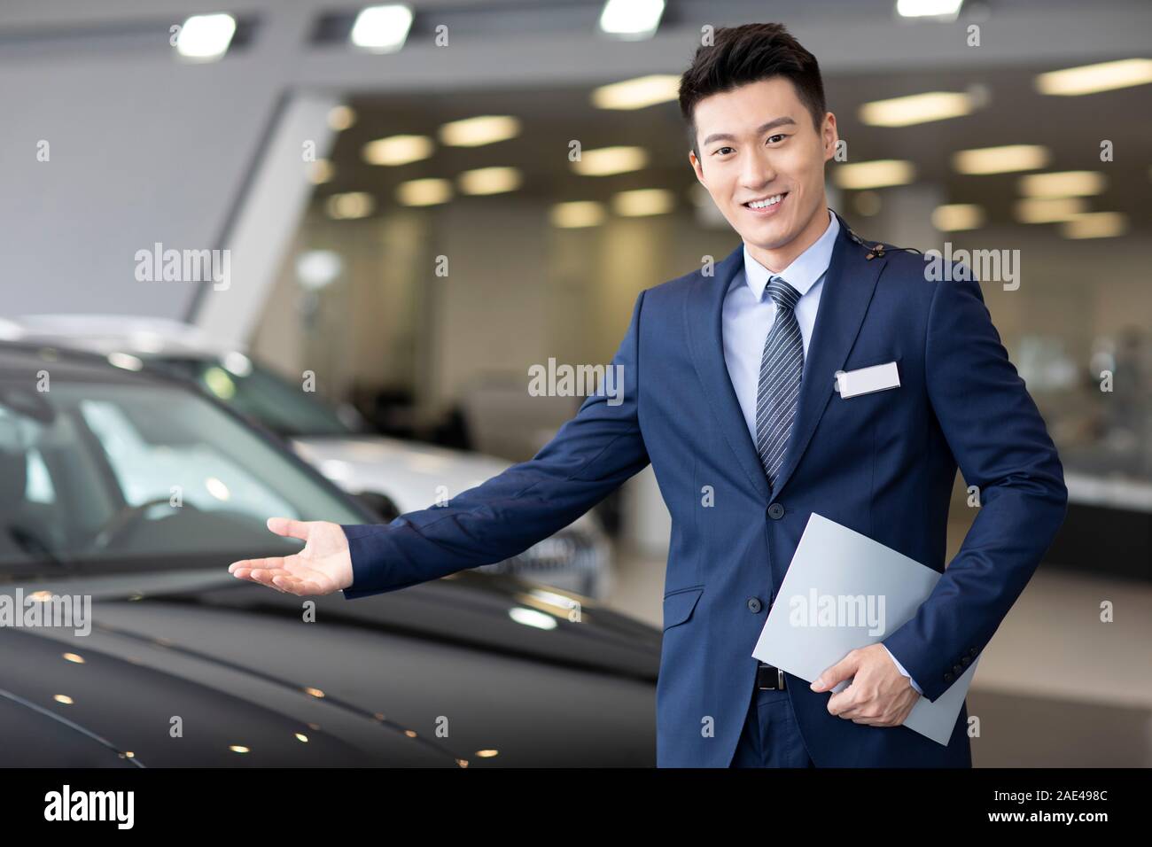 Confident salesman with cars in showroom Stock Photo - Alamy