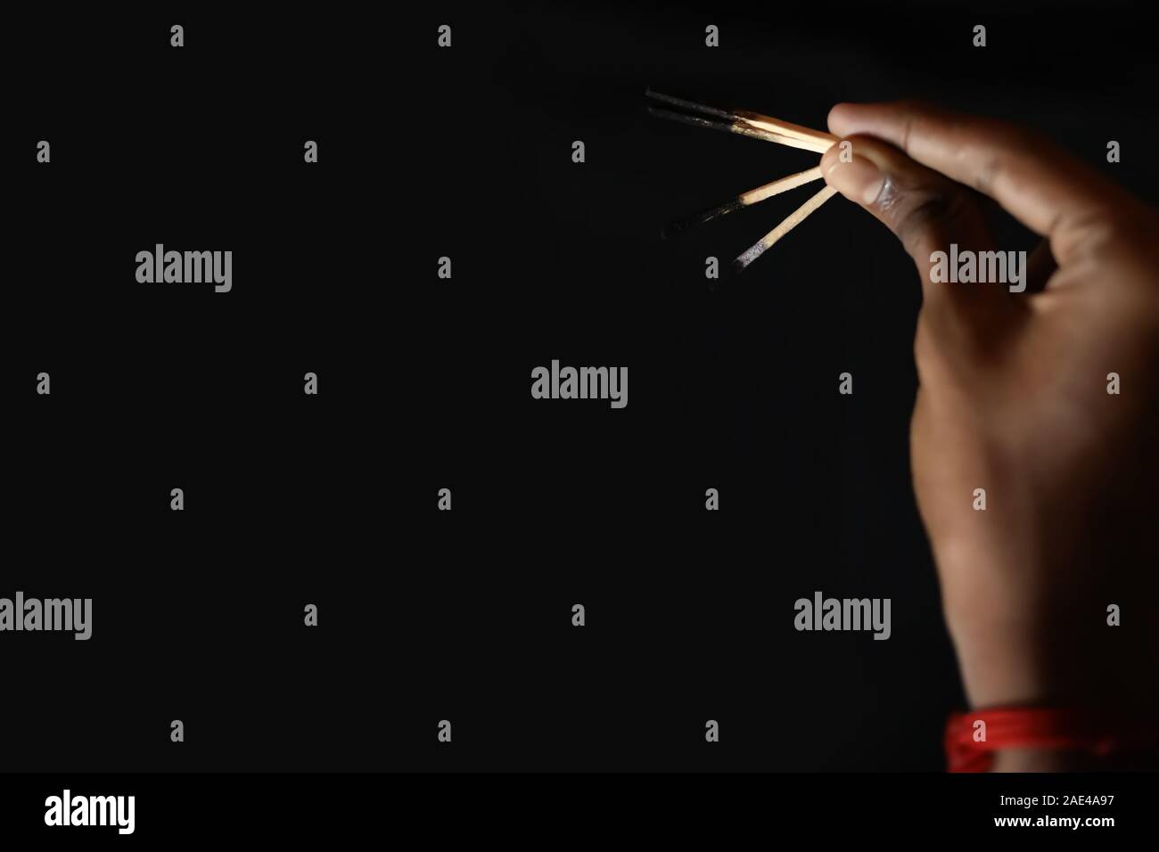 Hand holding an extinguished matchstick on black background Stock Photo ...