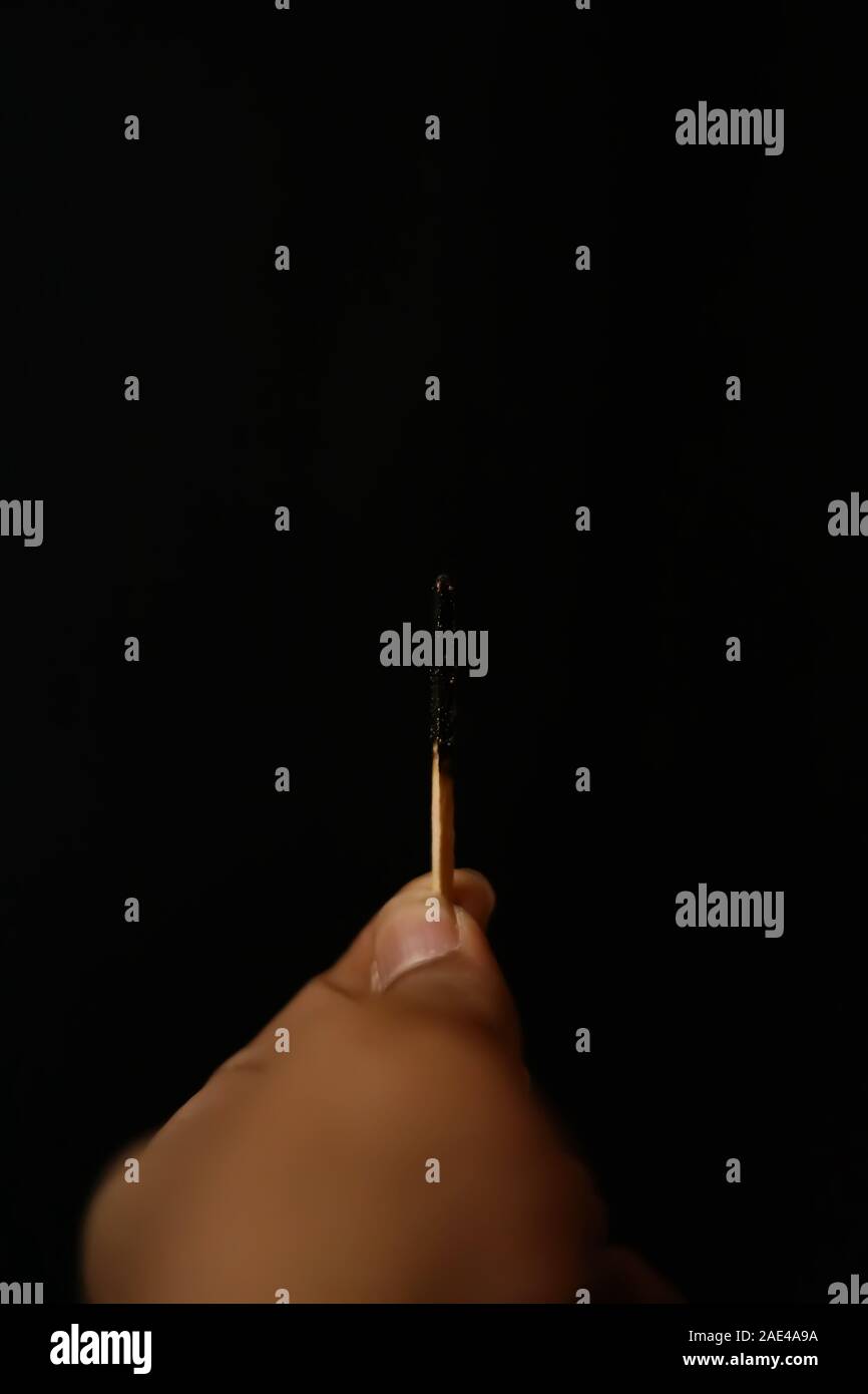 Hand holding an extinguished matchstick on black backgrounds Stock ...