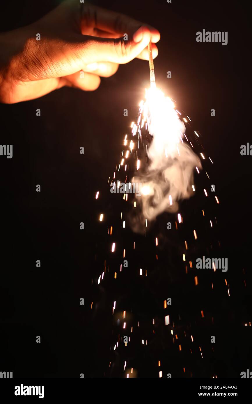 Hand holding burning Sparkler blast on a black background at night ...