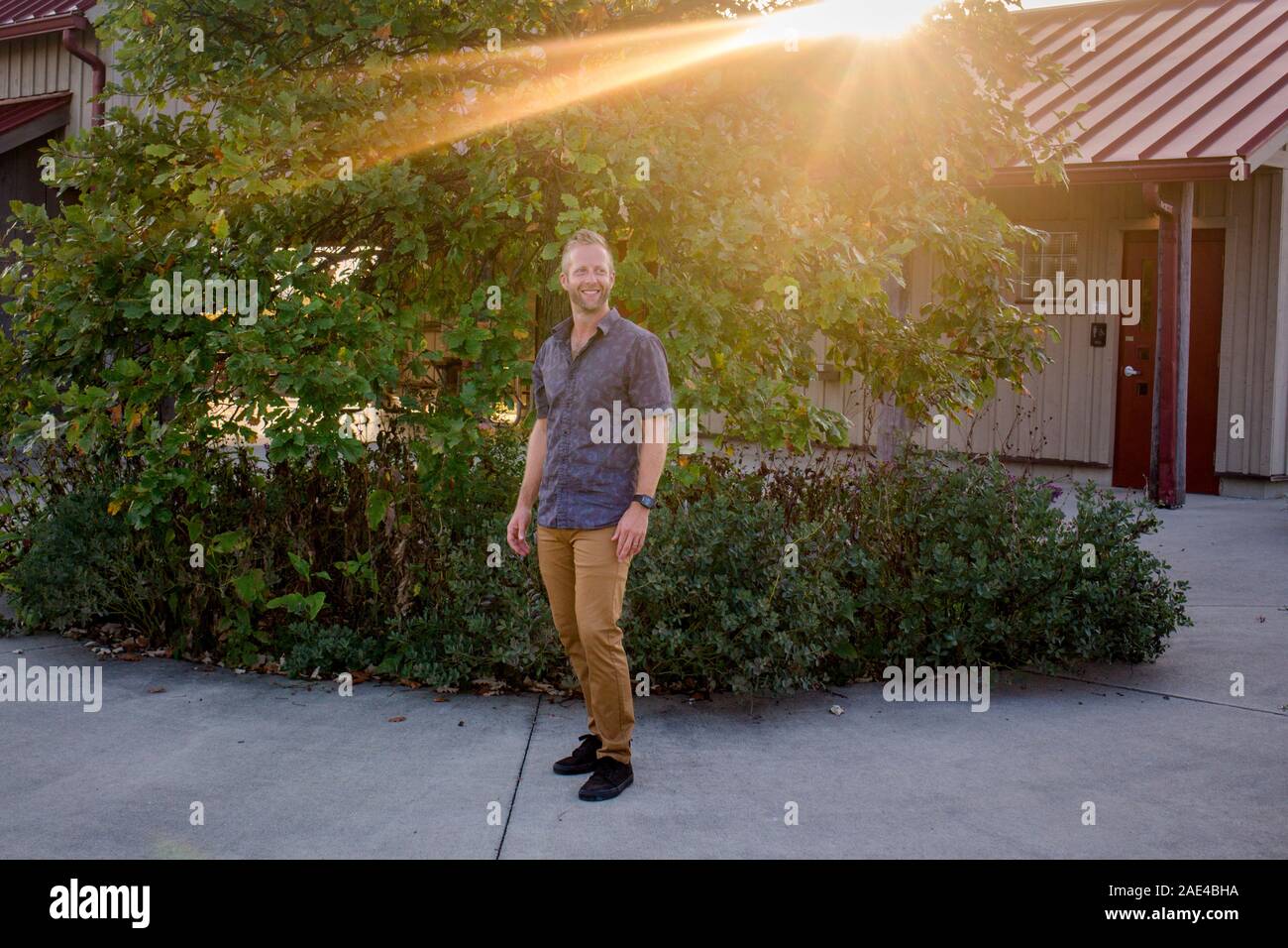 A proud man stands smiling in front of his home at sunset Stock Photo ...