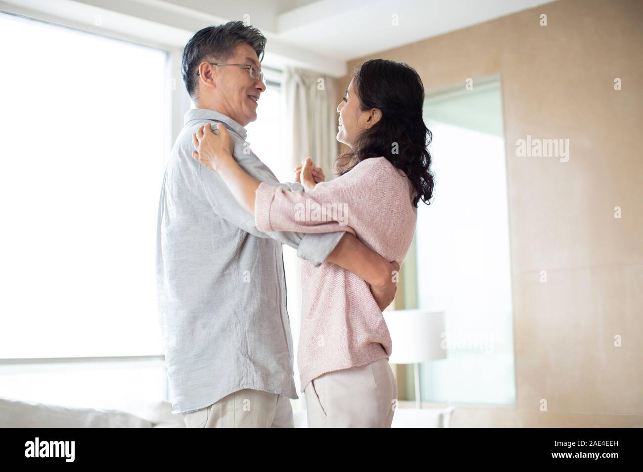 Happy mature couple dancing in living room Stock Photo - Alamy