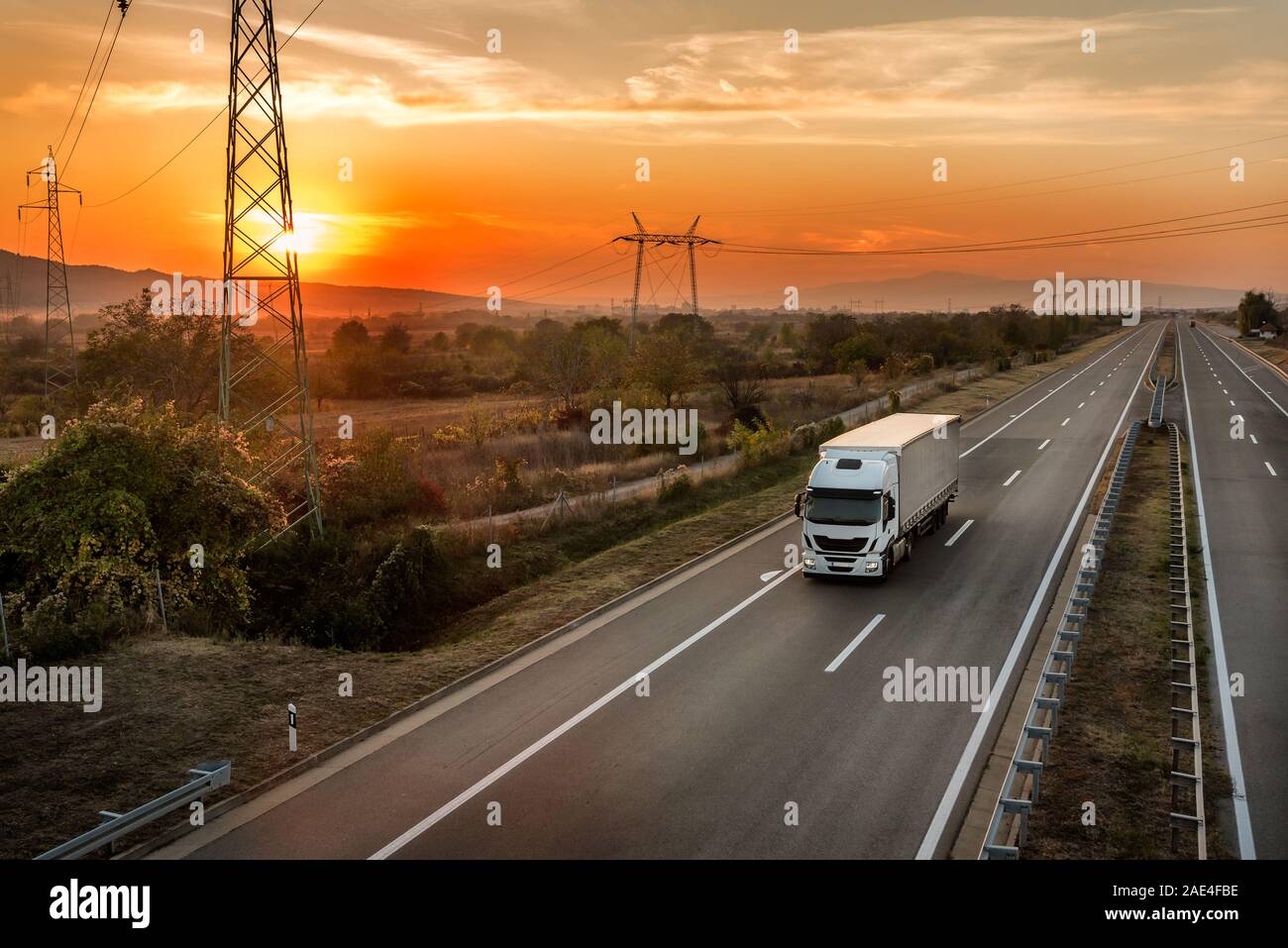 Single lorry truck on a country highway under amazing orange sunset sky ...