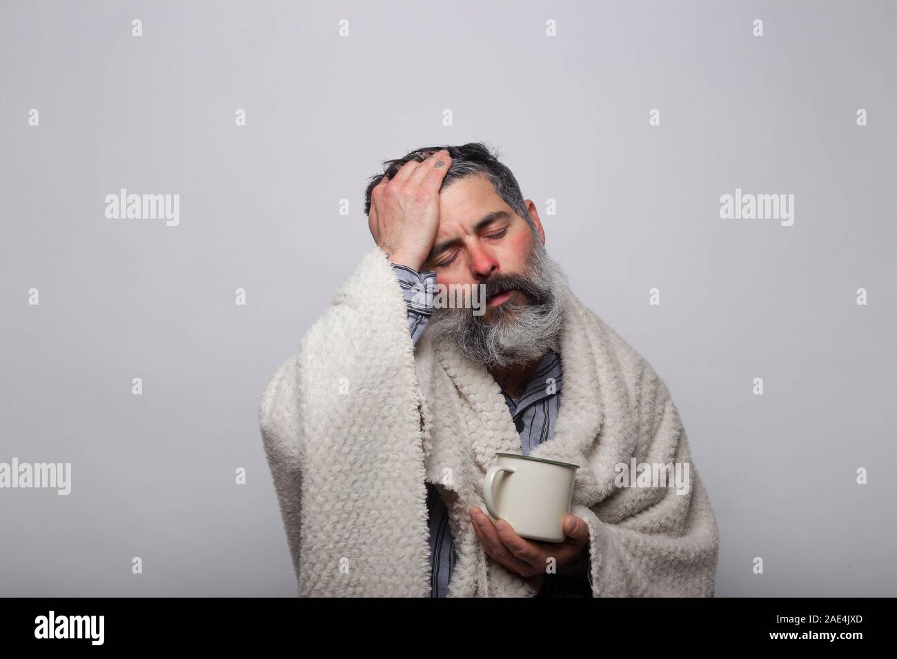 Headache man. Photo of a sick man wrapped in a blanket with a cup of ...