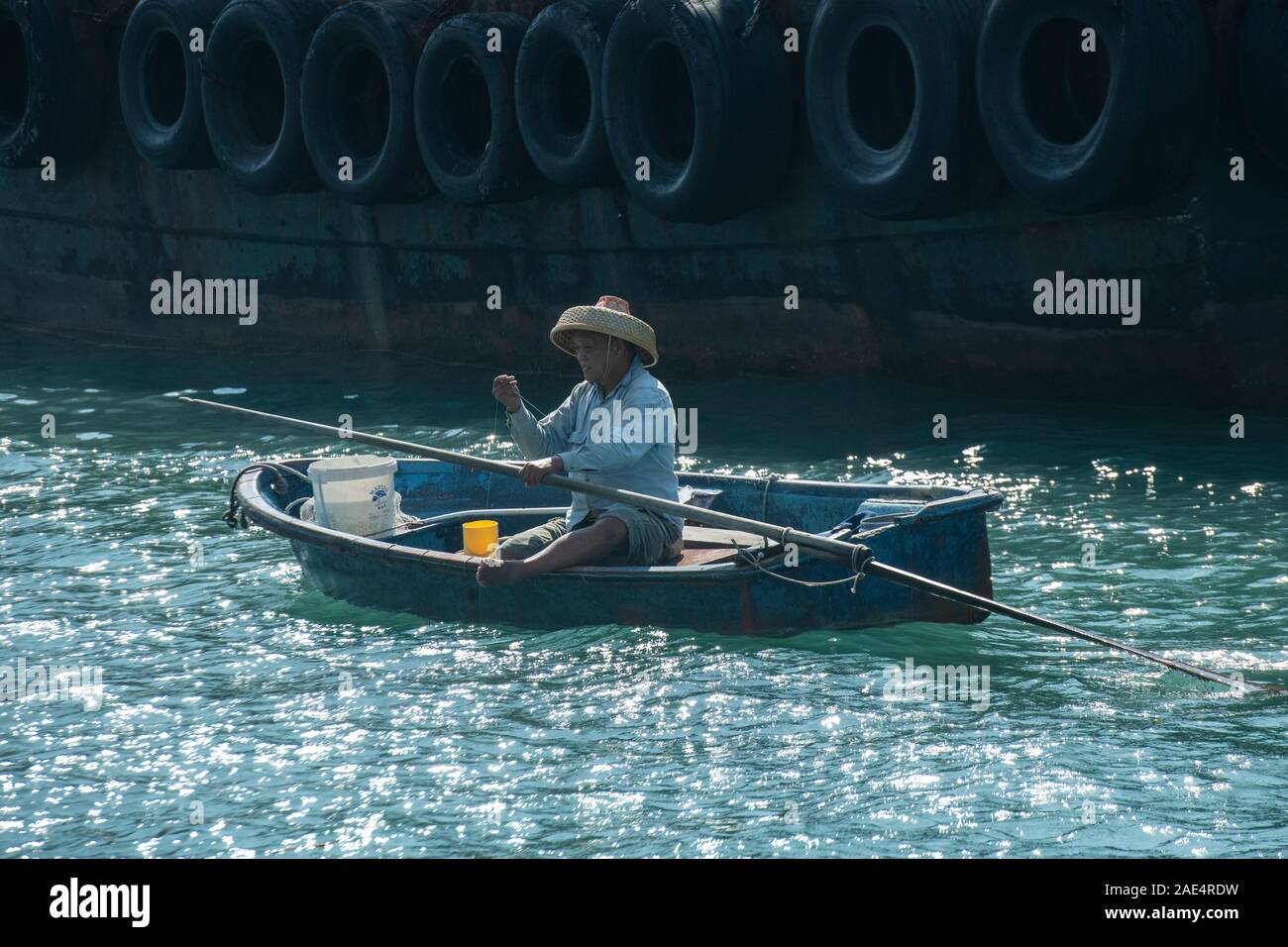 A commercial fisherman uses a hand line on a very small fishing boat in ...