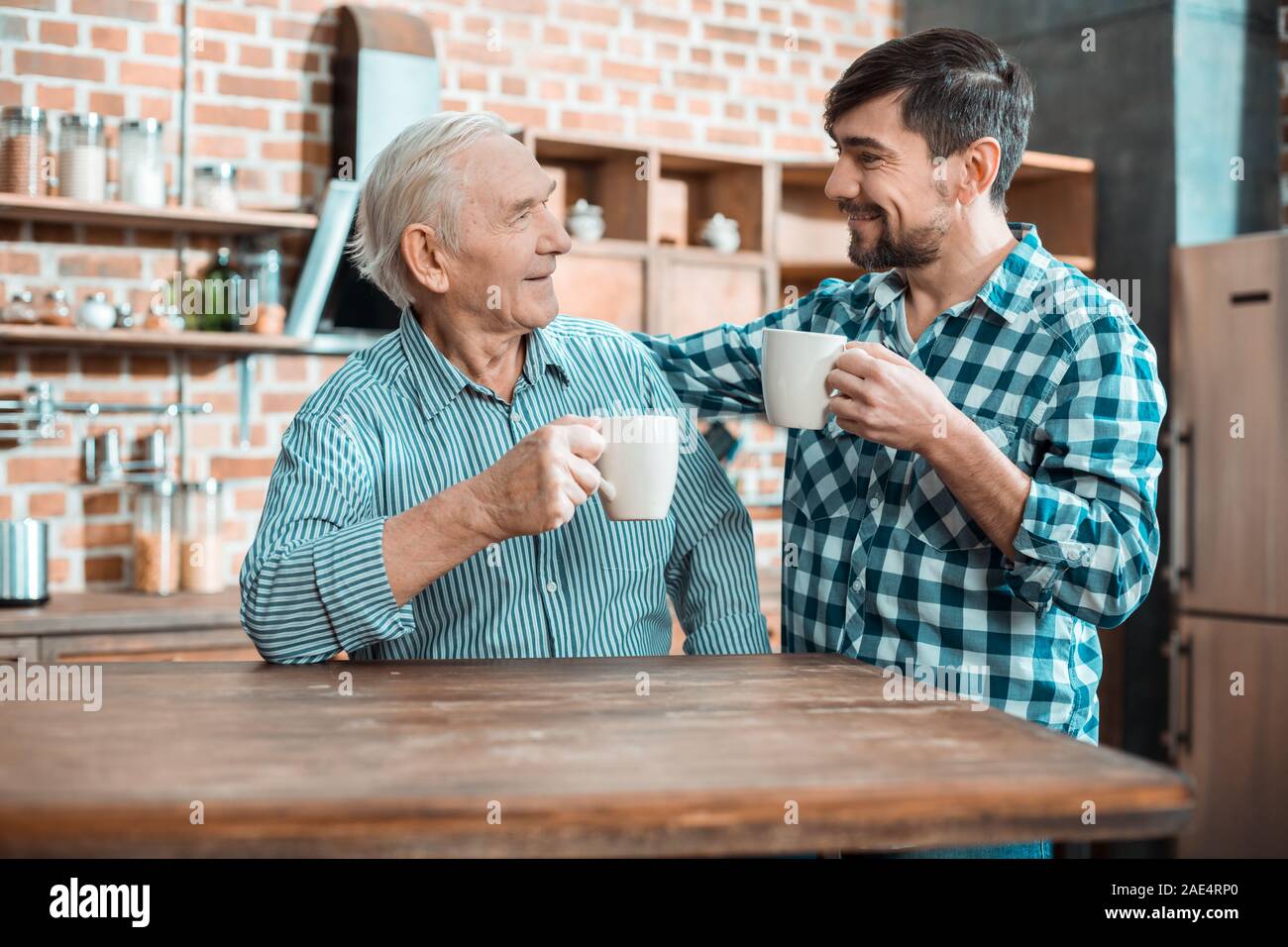 Happy nice father and son having tea Stock Photo - Alamy