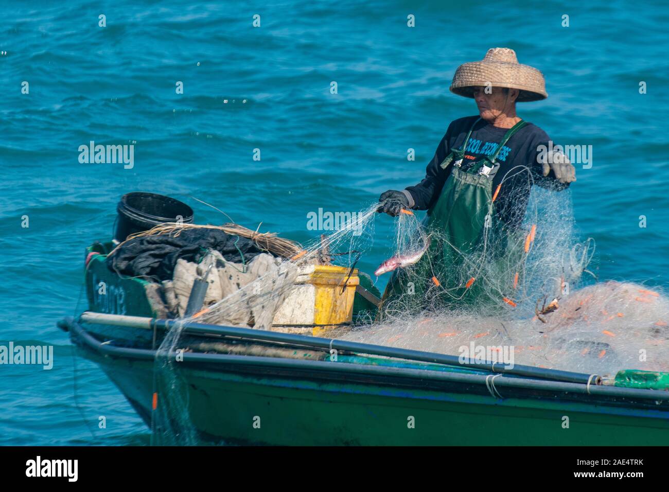 A commercial fisherman using nets on a very small fishing boat - Hong ...