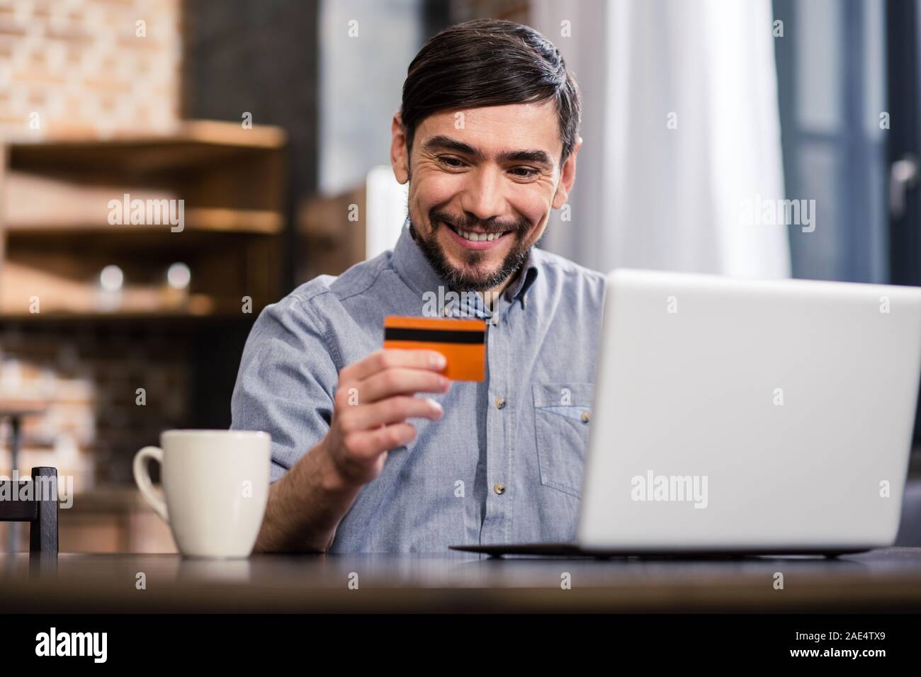 Positive young man utilizing online banking Stock Photo - Alamy