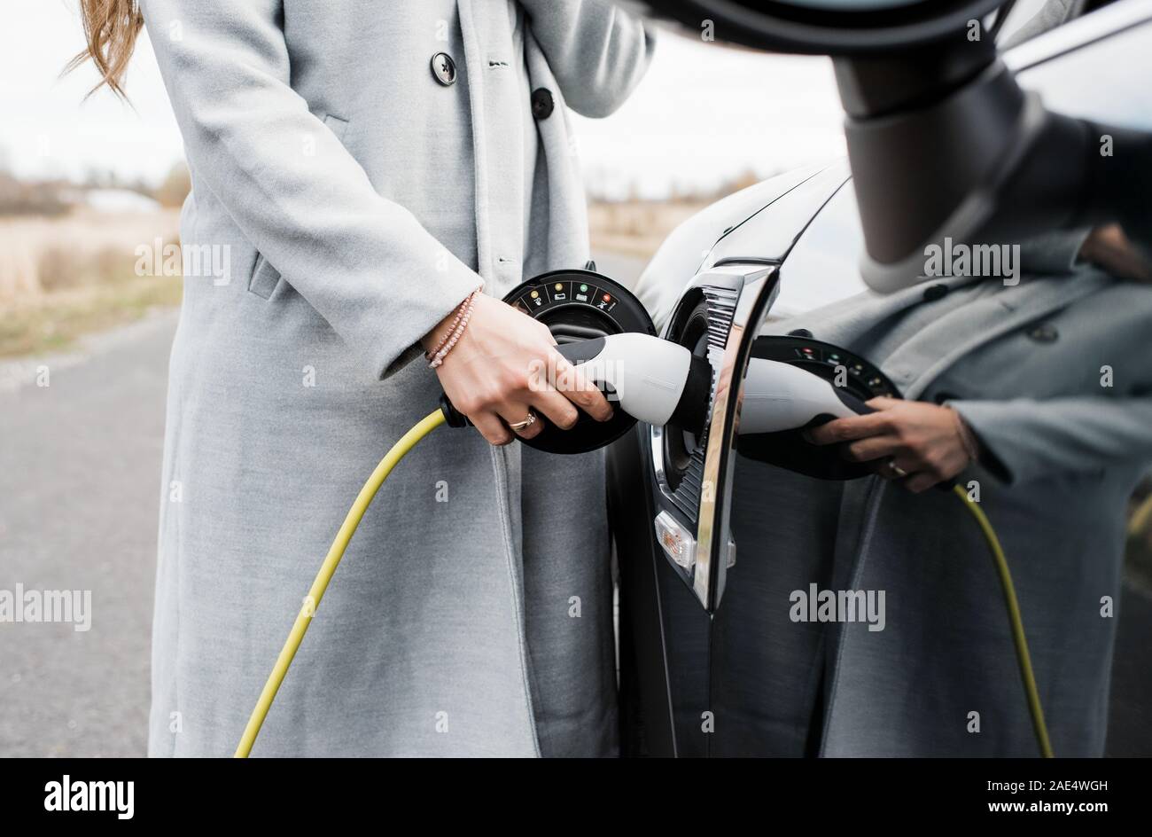 view of woman's hand plugging in charging lead to her electric car ...
