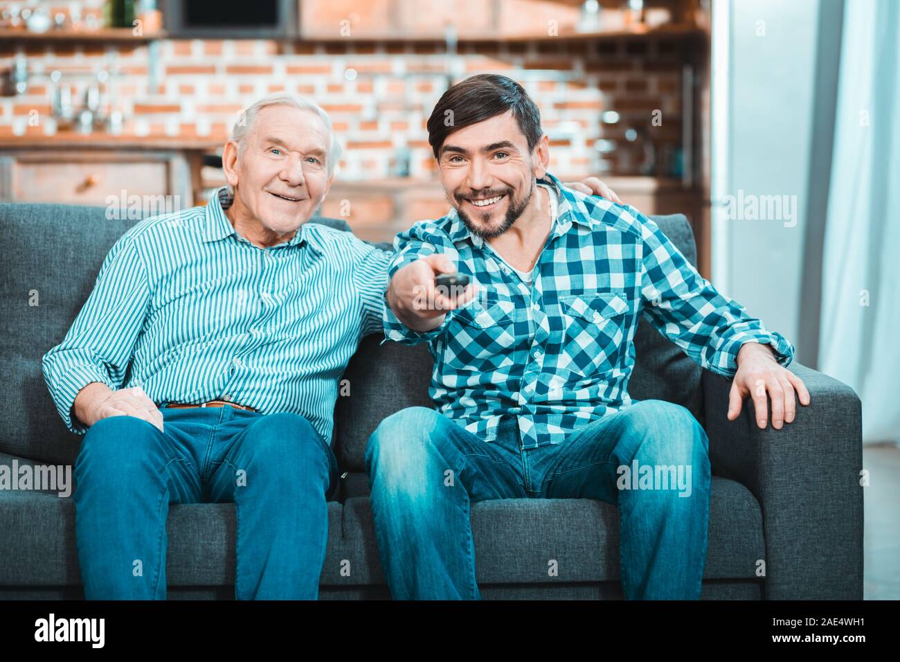 Happy positive man holding a remote control Stock Photo - Alamy