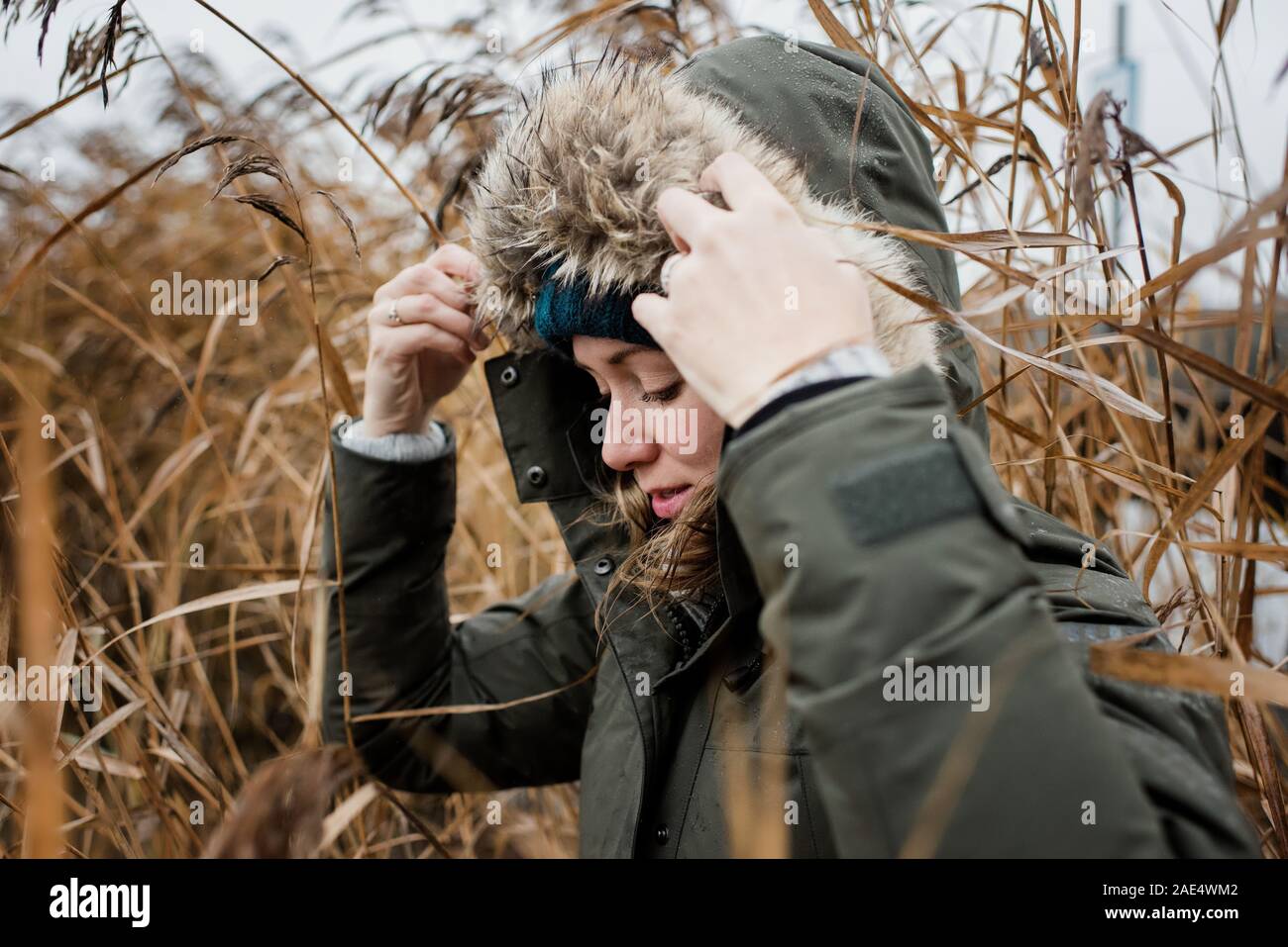 portrait of a woman pulling her hood over her head at the beach Stock ...