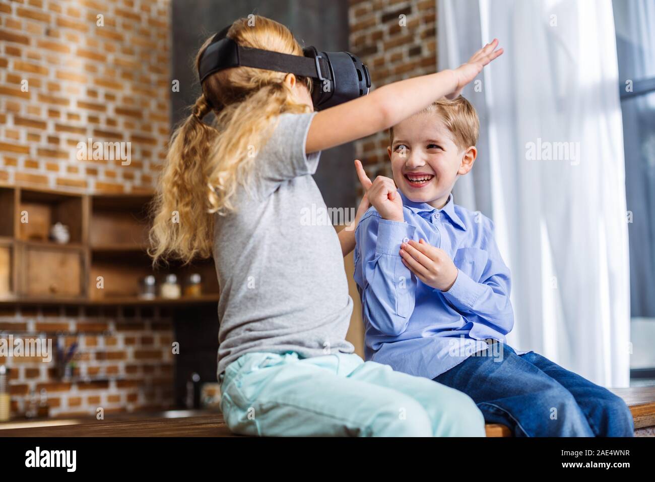 Happy little siblings sitting in the kitchen with VR glasses Stock ...