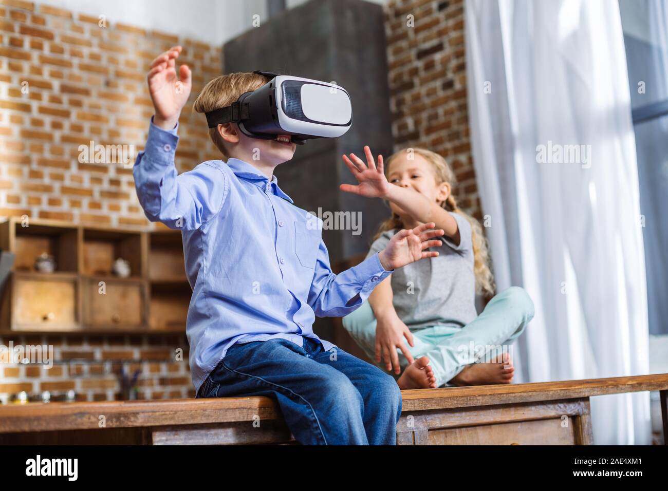 Low angle of cheerful little siblings testing VR glasses Stock Photo ... Low angle of cheerful little siblings testing VR glasses Stock Photo ...