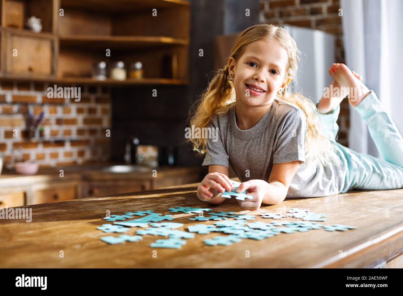 Positive little girl playign with jigsaw puzzles Stock Photo - Alamy