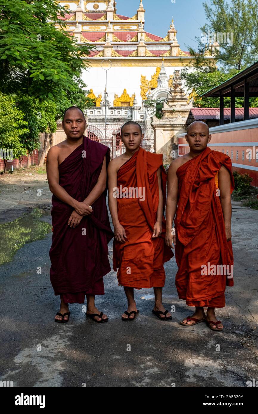 Three Buddhist monks leave the grounds of Kyauk Taw Gyi Pagoda dressed ...