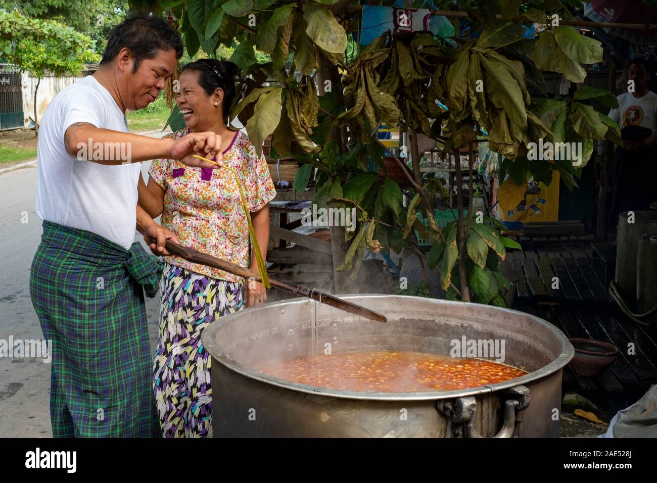 A wife and husband prepare a large pot of soup on the street to feed ...