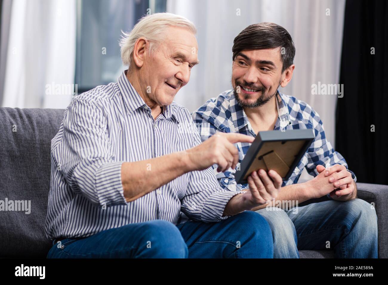 Positive father and son looking at a photo frame Stock Photo - Alamy