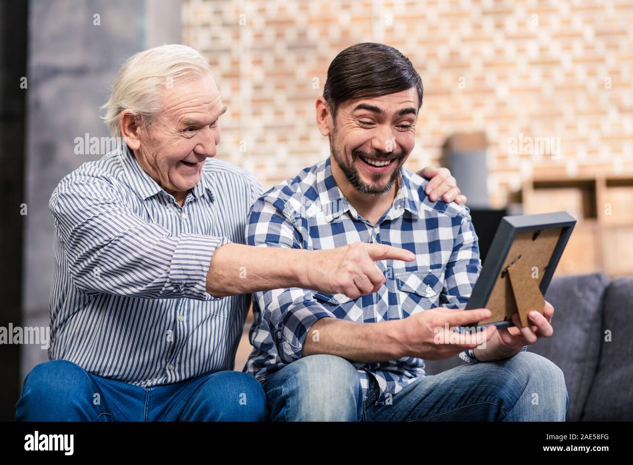 Joyful father and son looking at a photo frame Stock Photo - Alamy
