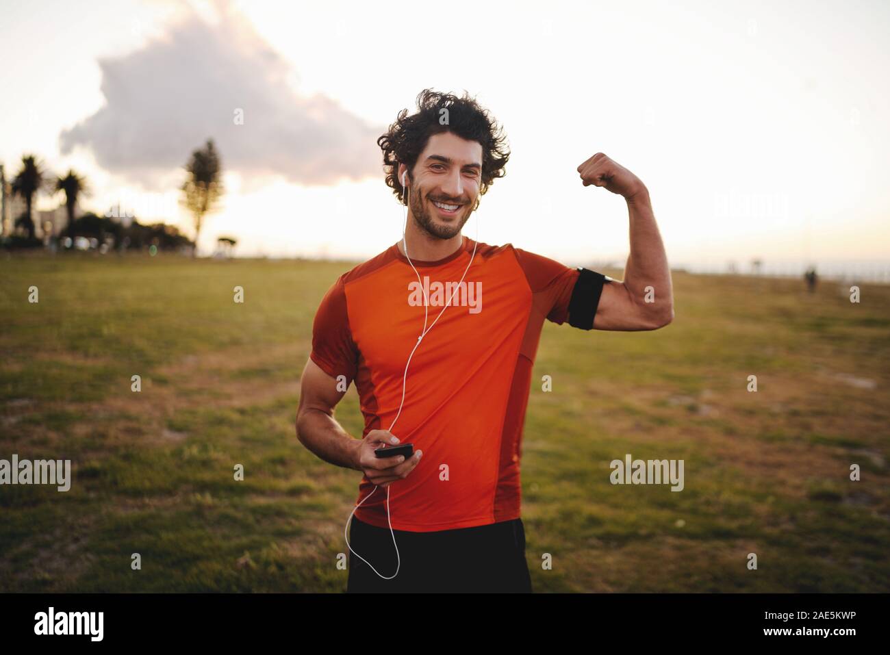 Smiling portrait of a male runner listening to music on earphones and ...
