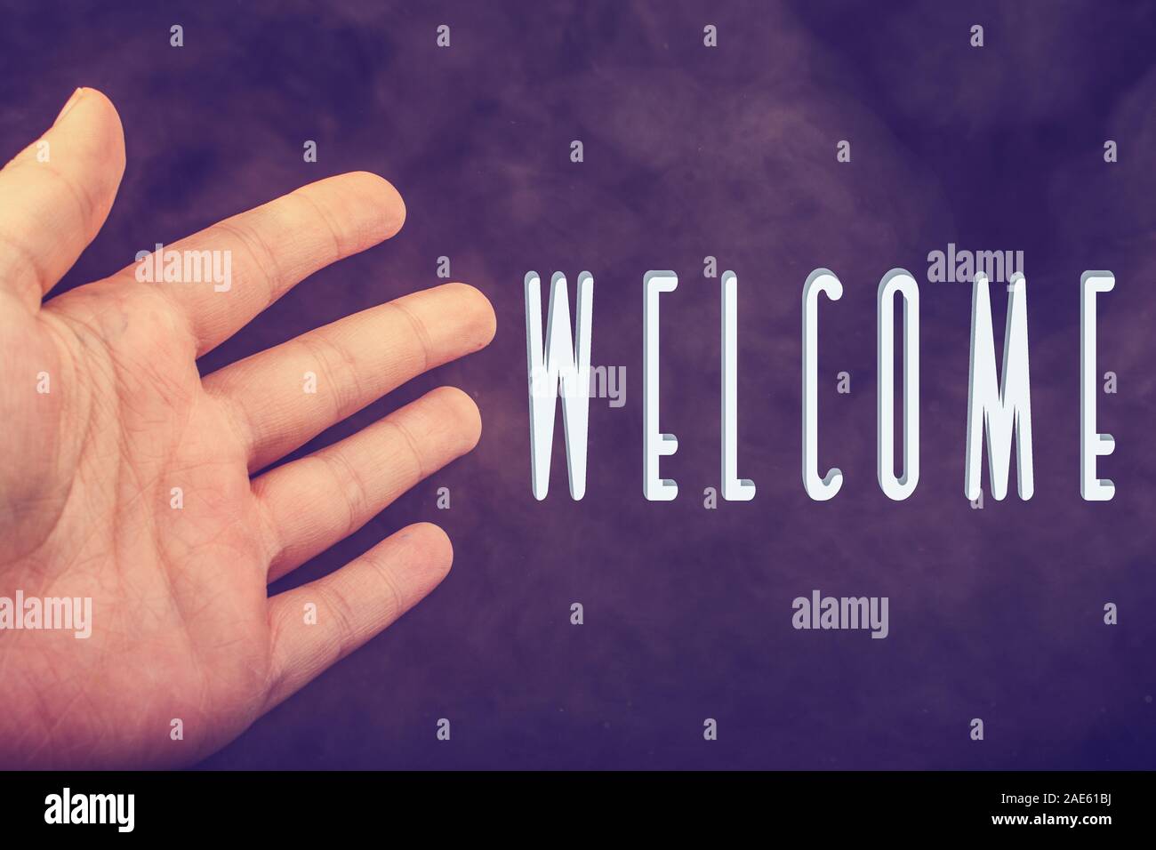 Hand making a welcome gesture on a dark background Stock Photo - Alamy