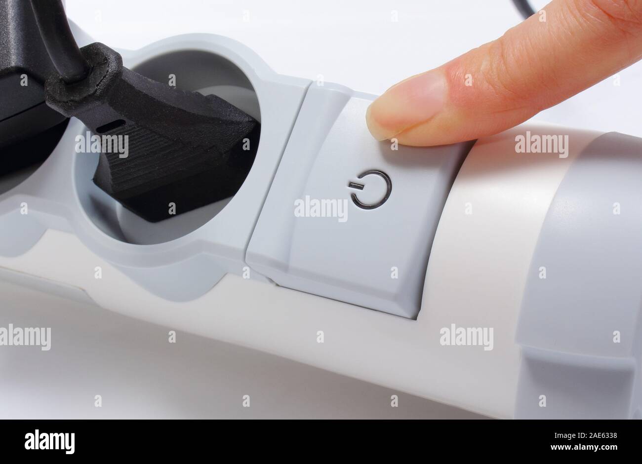 Finger of woman turns off electrical extension with connected plugs ...