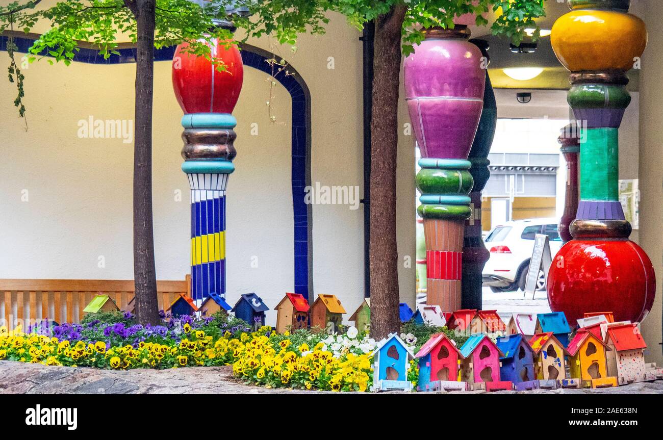 Colourful ceramic tiled columns and a row of birdhouses in a courtyard ...