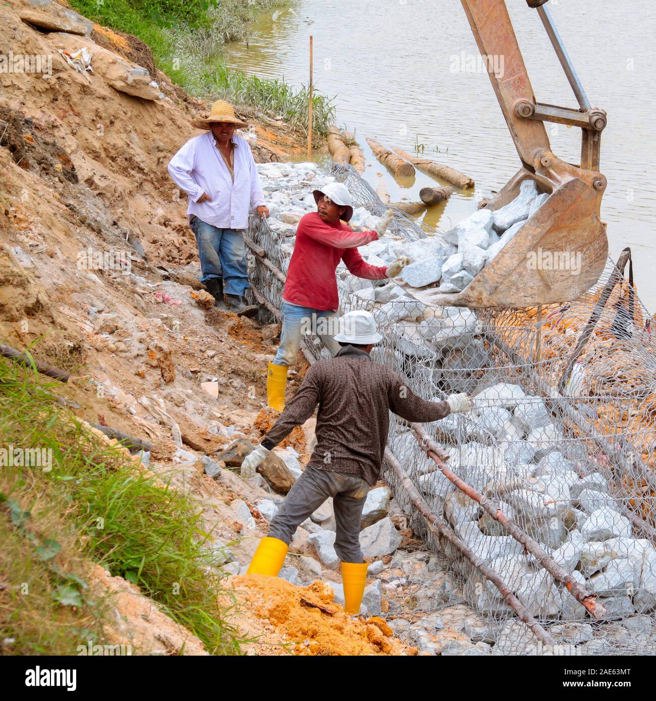 Construction worker building a river bank barrier with the help of an ...