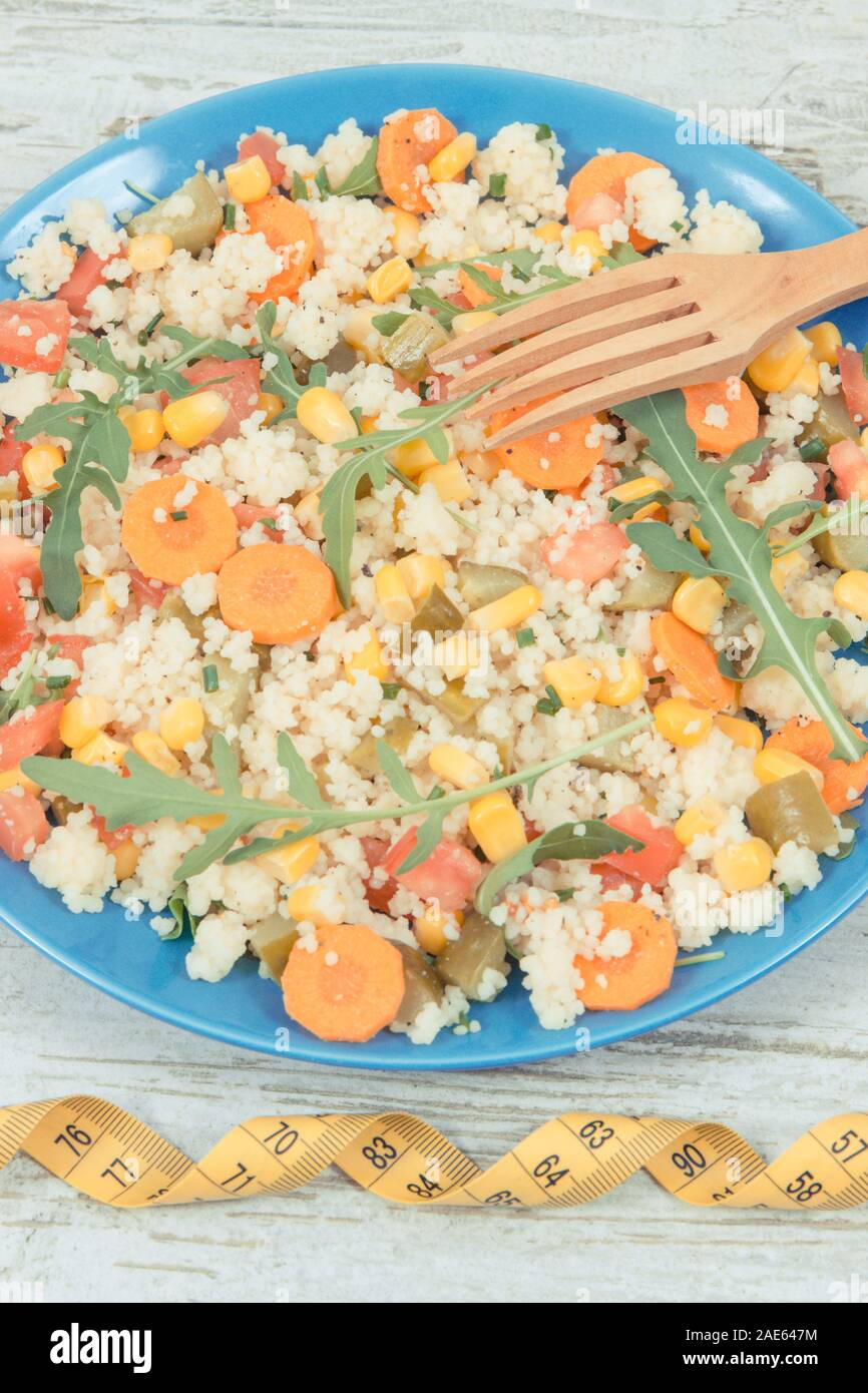 Tape measure and fresh salad with vegetables and couscous groats. Light ...