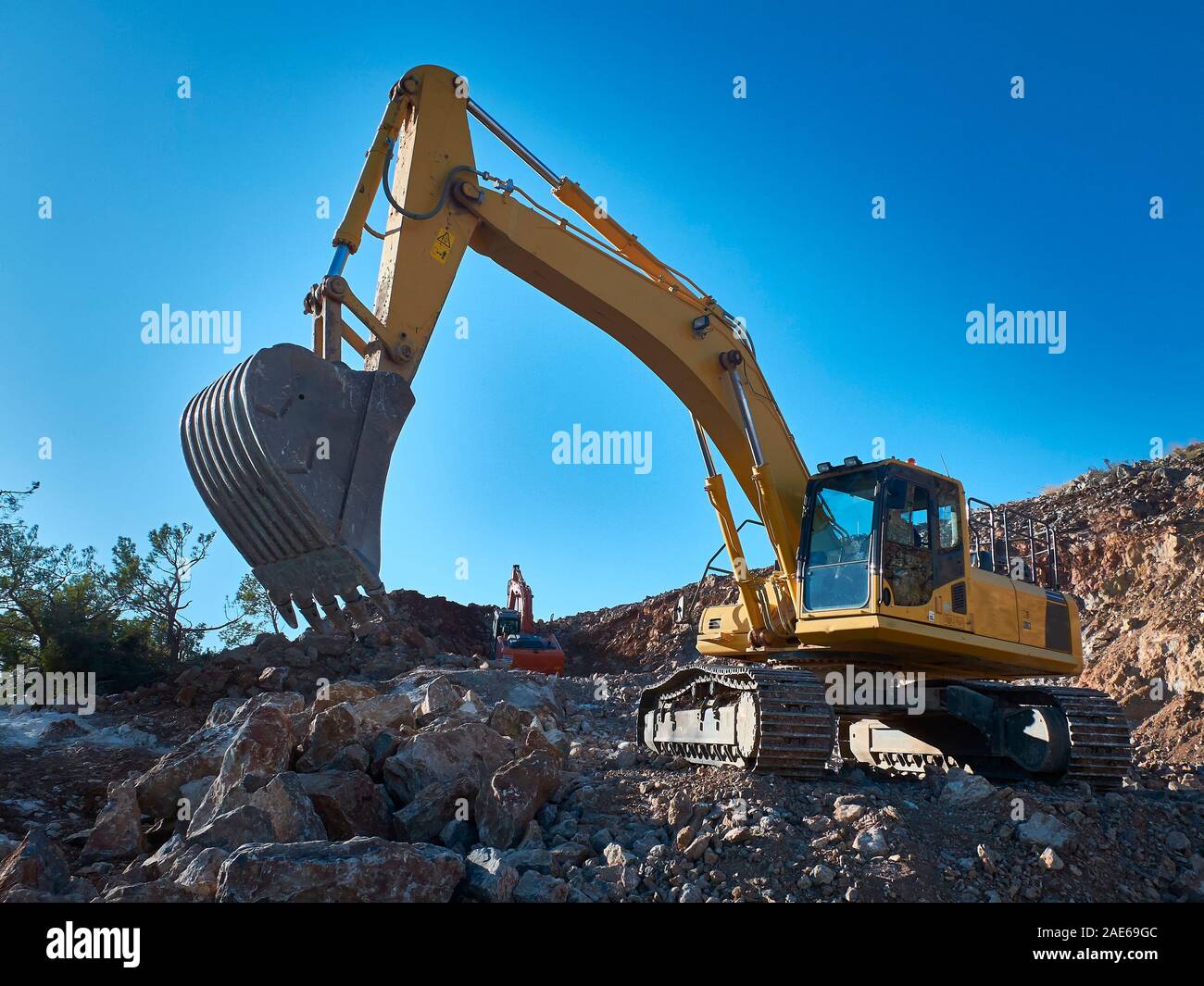 Excavator is moving a rock boulders during road construction on the ...