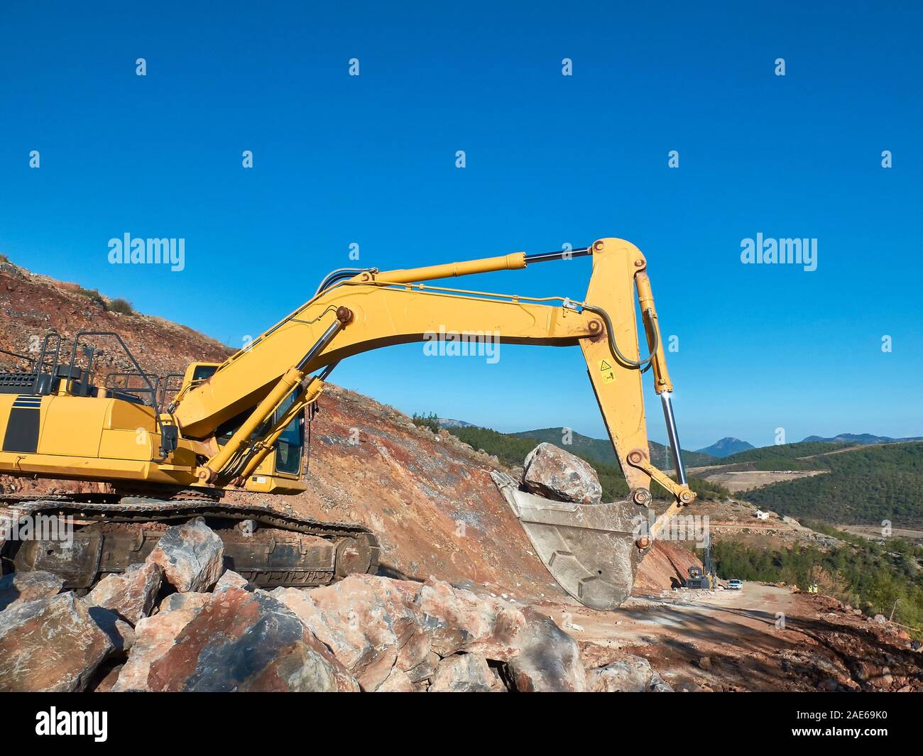 Excavator is moving a rock boulders during road construction on the ...