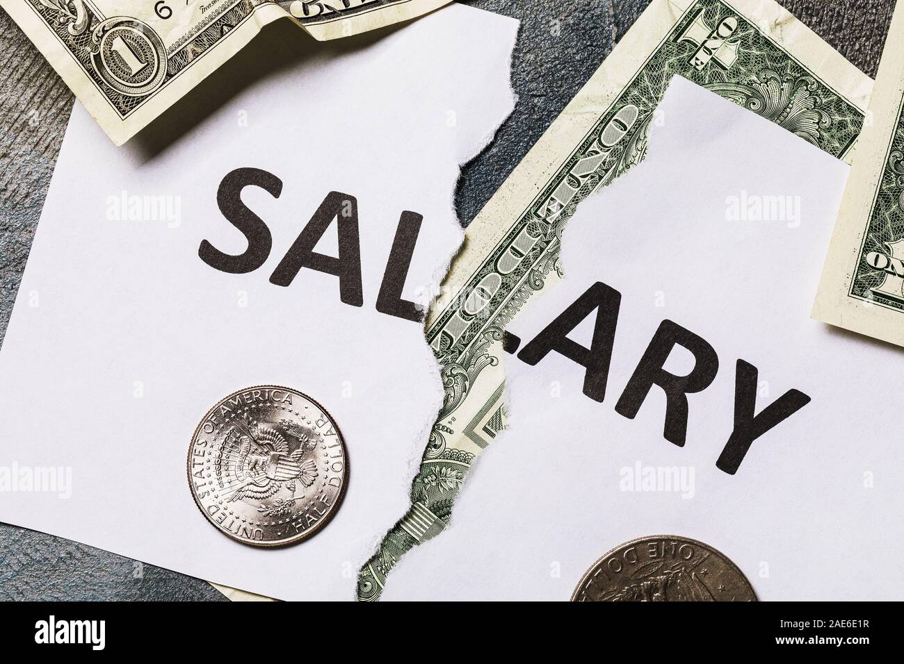 A sheet of white paper with the words salary, torn in half. Low salary ...