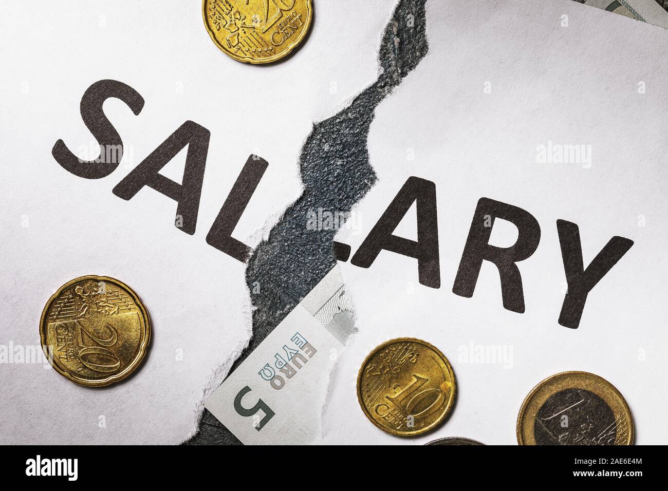 A sheet of white paper with the words salary, torn in half. Low salary ...