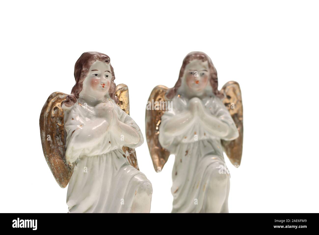 Two porcelain angels in a prayer pose isolated on a white background ...