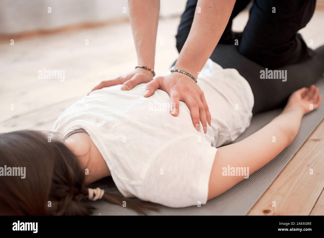 Man does back massage of brunette woman lying on gray rug in gym Stock ...