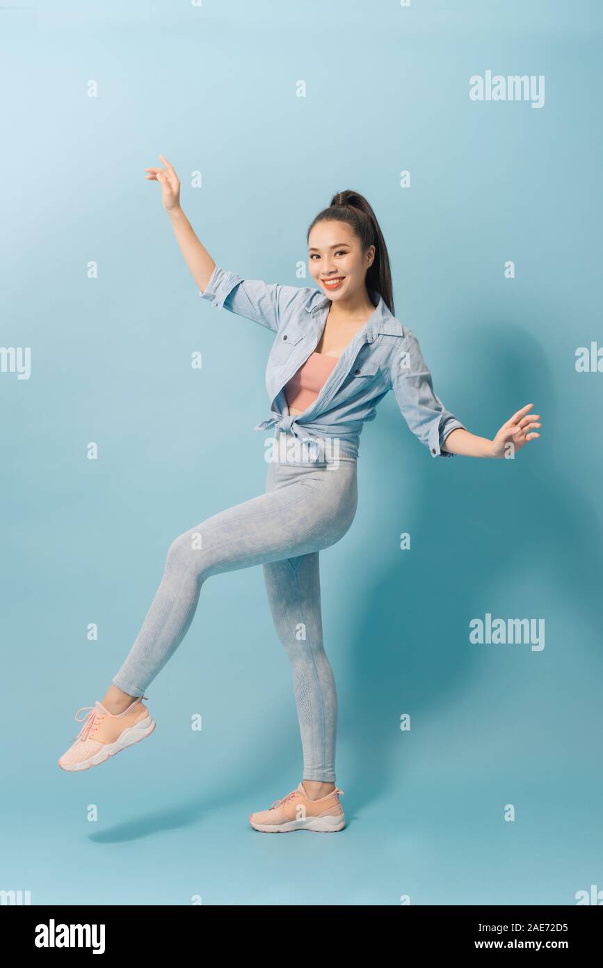 Charming excited crazy woman jumping up on light blue background Stock ...