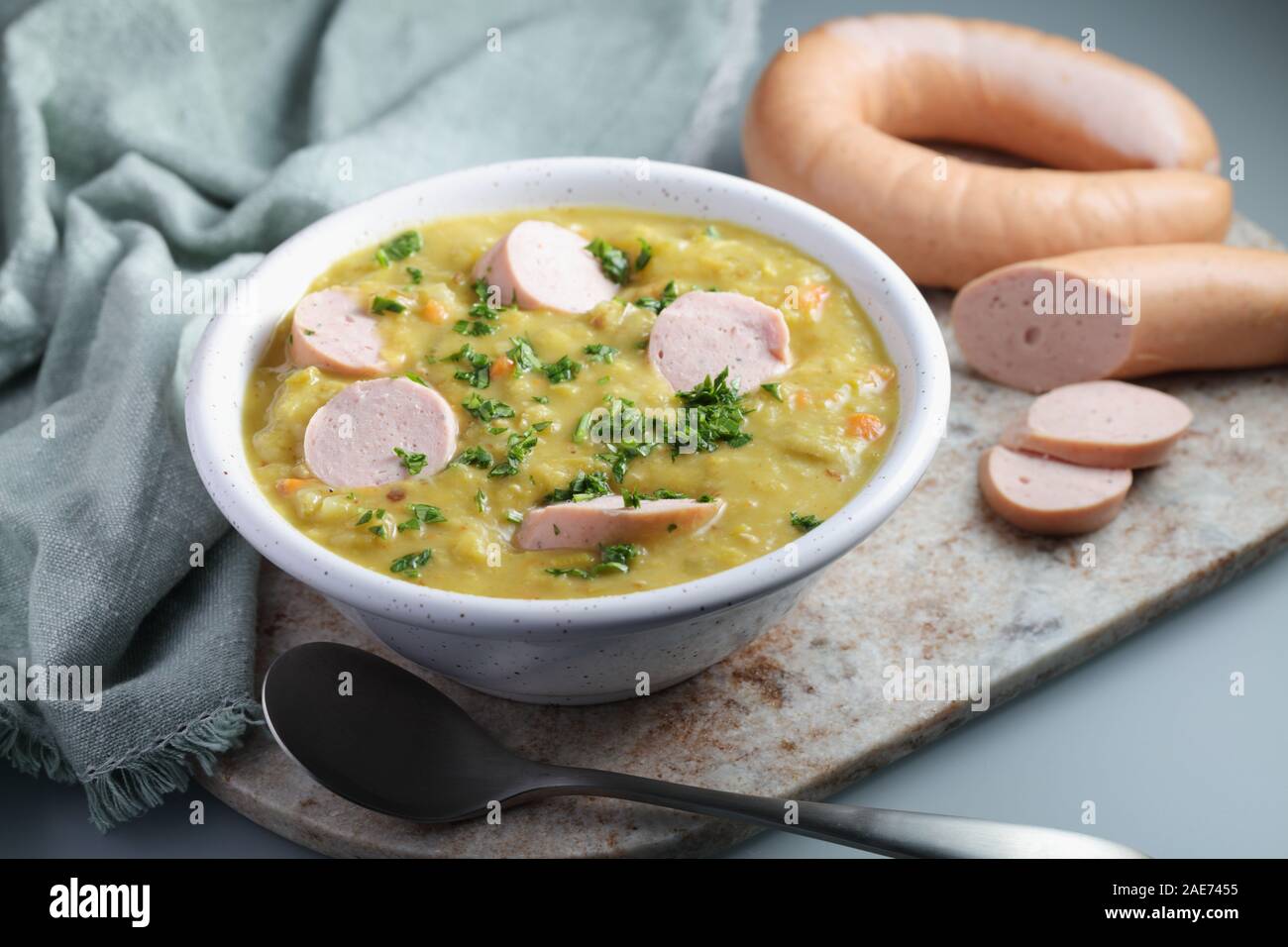 Dutch pea soup Snert with smoked sausage Rookworst on a rustic table ...