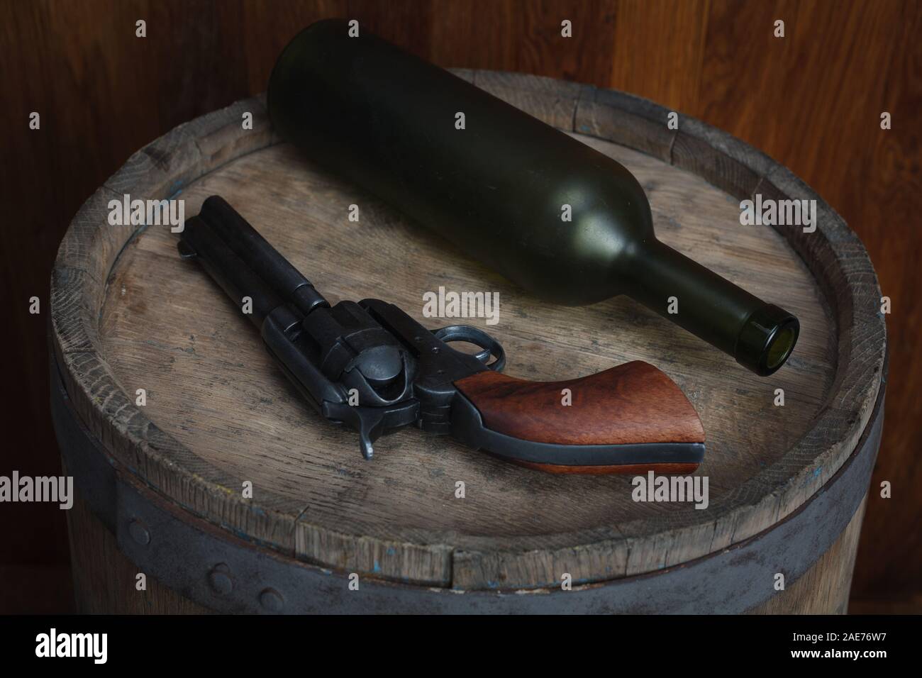 Old western revolver with bottle on wooden barrel Stock Photo - Alamy