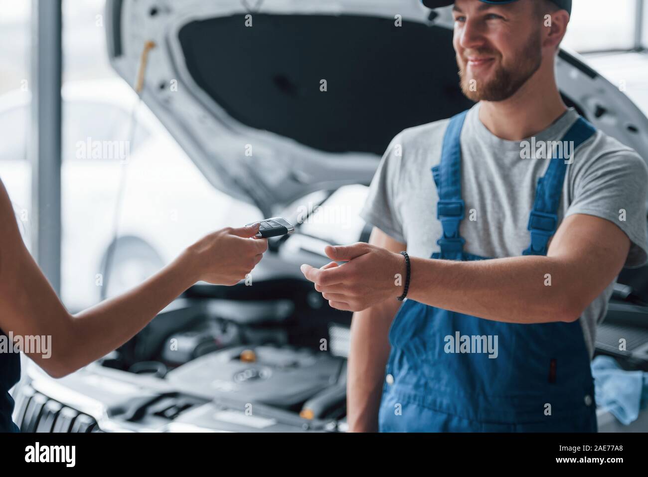 Nice work. Woman in the auto salon with employee in blue uniform taking ...