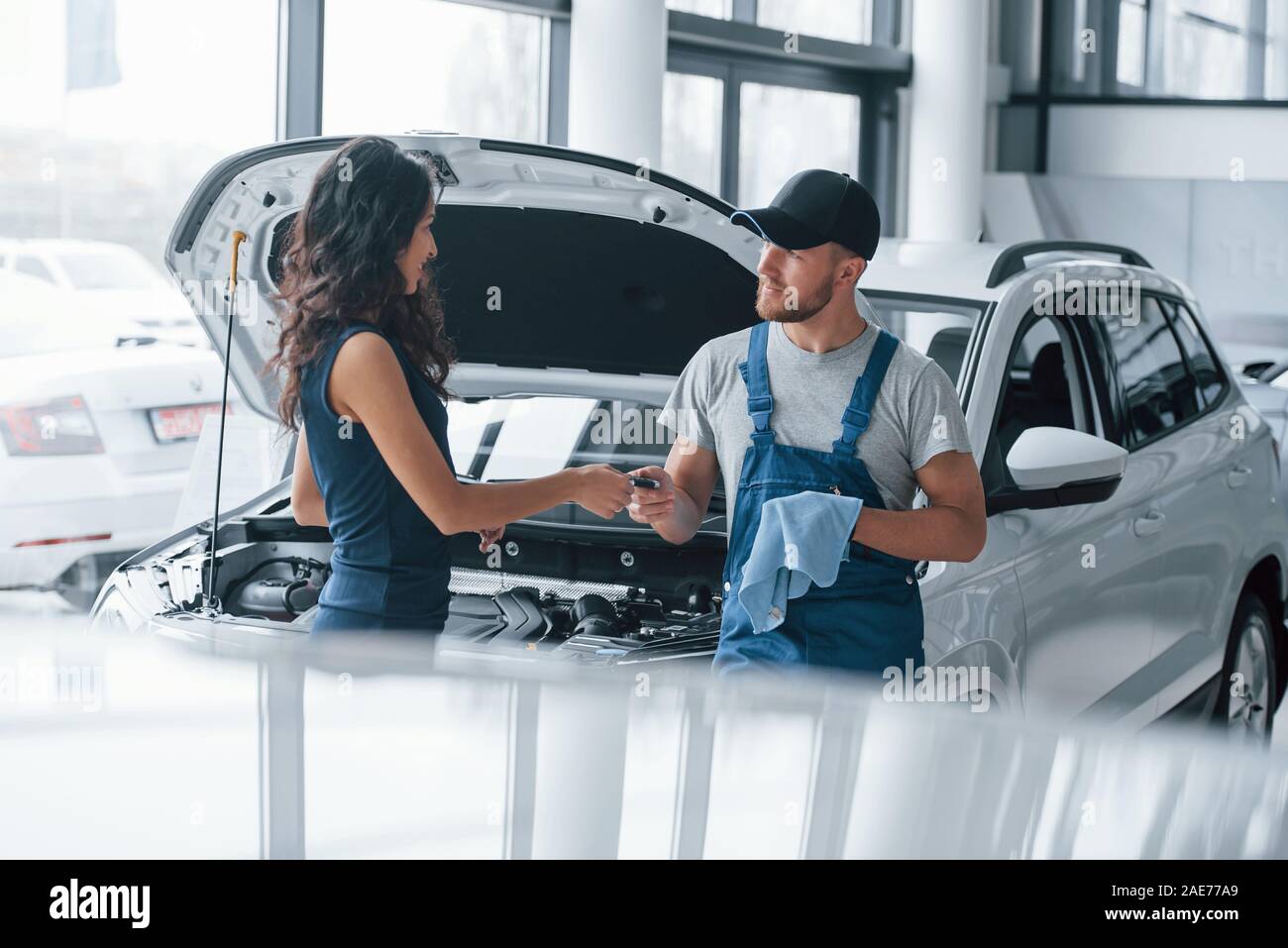 Trust and occupation. Woman in the auto salon with employee in blue ...