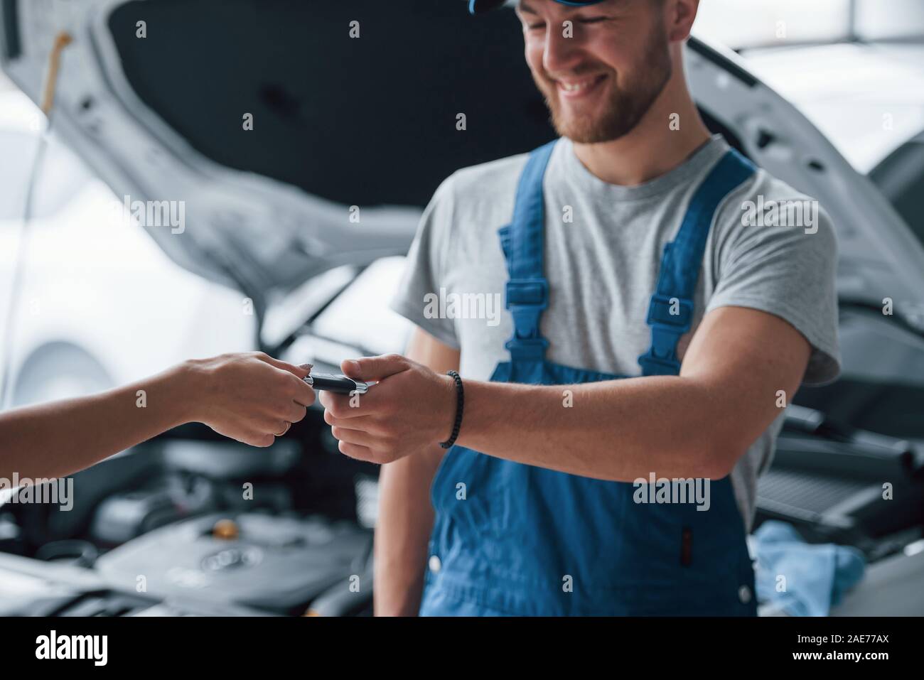 Eyes closed. Woman in the auto salon with employee in blue uniform ...