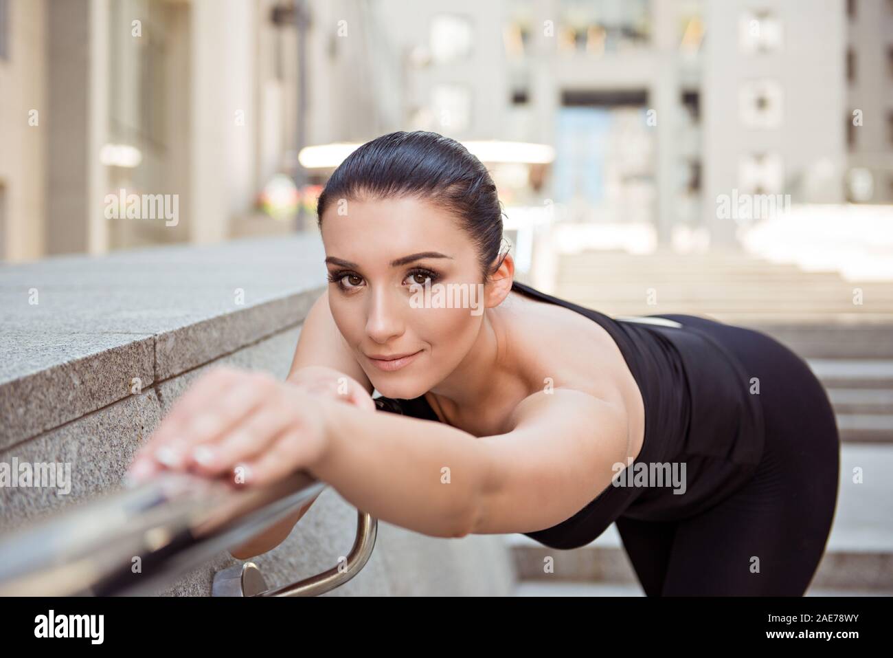 Flexible young woman leaning on the railing Stock Photo - Alamy