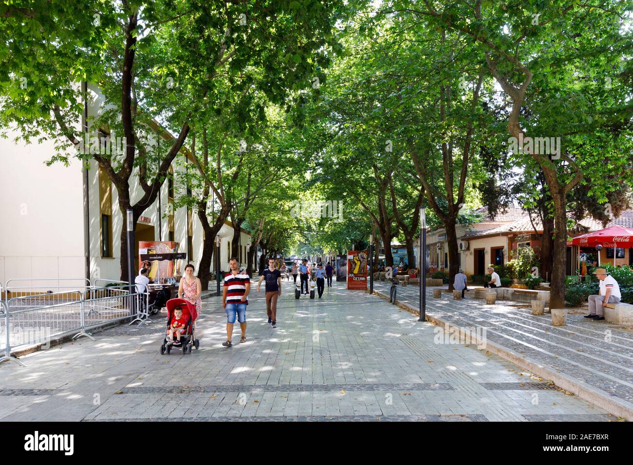 Tirana, Albania, July 8 2019: People walking at a pedestrian city street with trees in Tirana ...