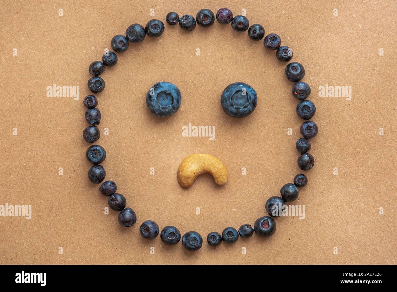 Sad face made from fresh variety of wild berries and nuts, healthy ...