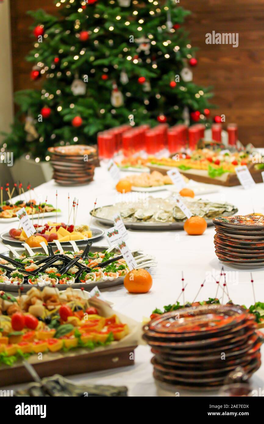 Christmas dishes and snacks at the party. Blurred decorated fir tree on ...