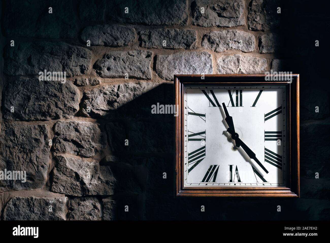 Square clock hanging on a stone wall Stock Photo - Alamy