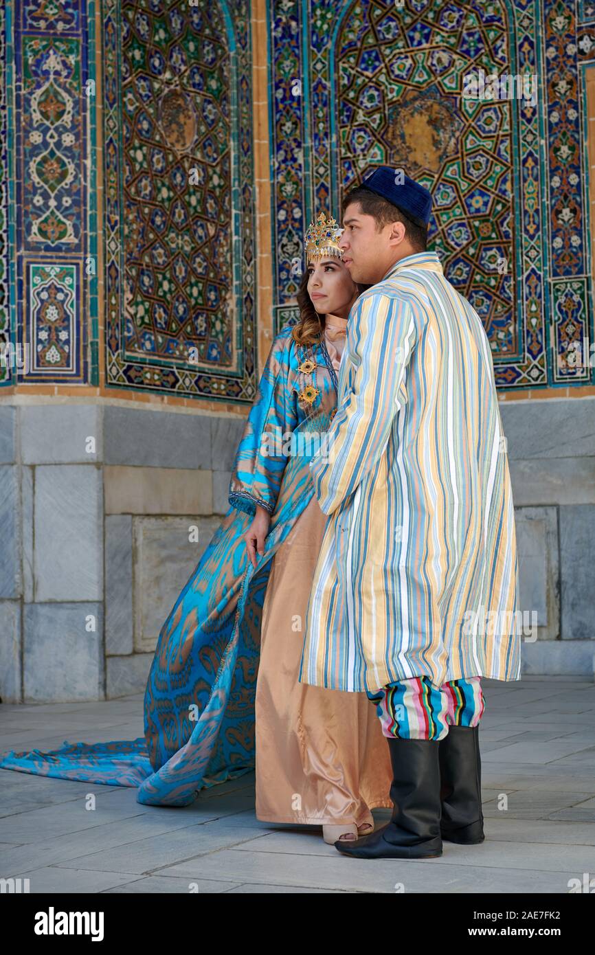bridal couple in traditional clothes posing in front of famous Registan ...