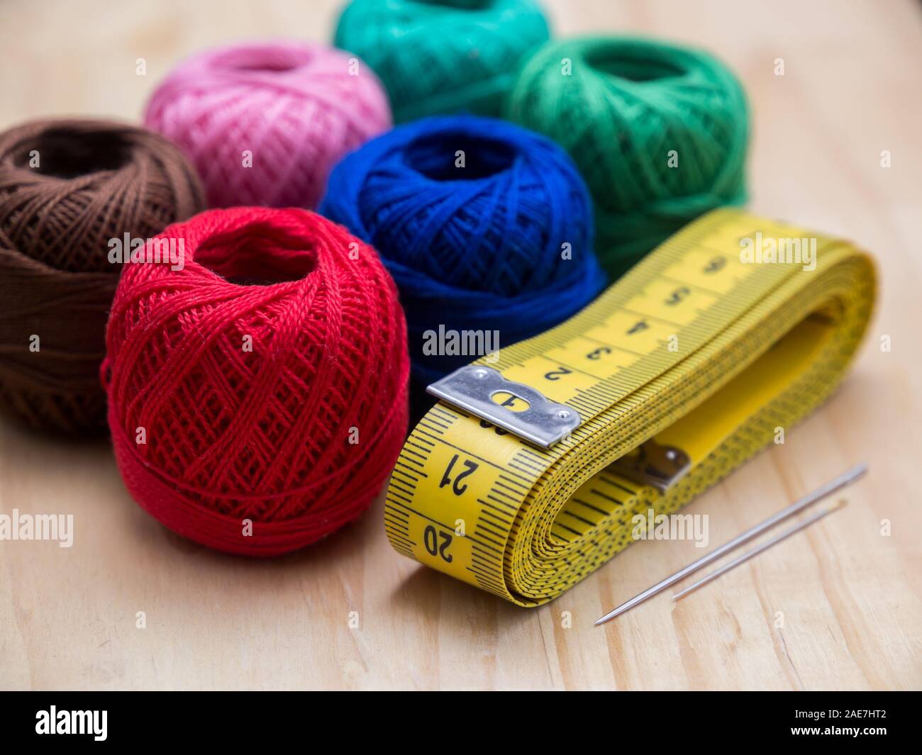 colored woolen thread and needles and meter close up on a wood ...