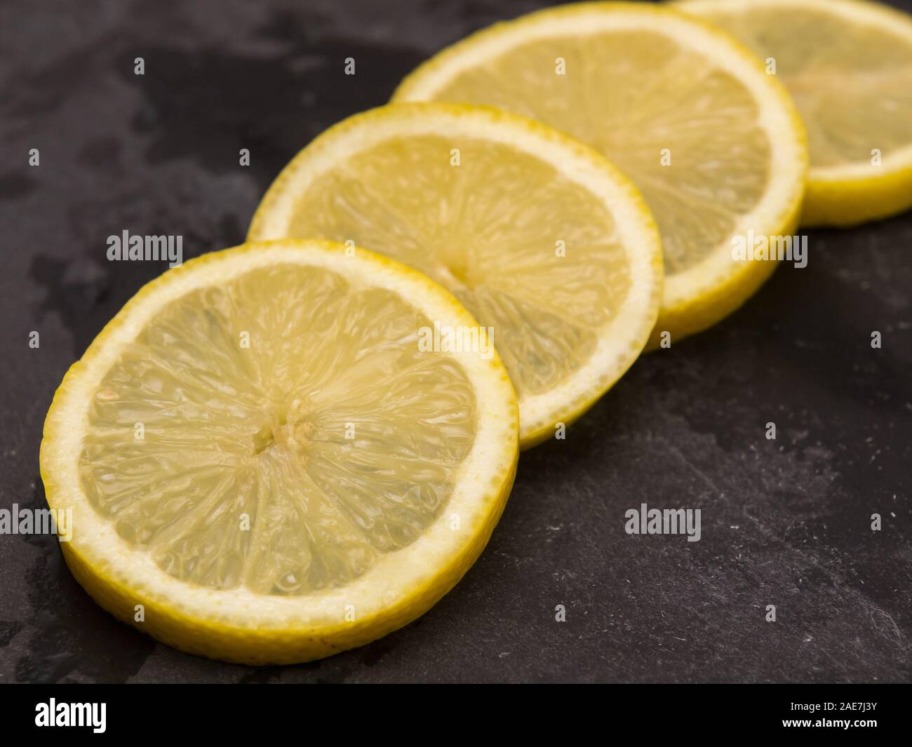 slices of lemon on slate wet stone Stock Photo - Alamy