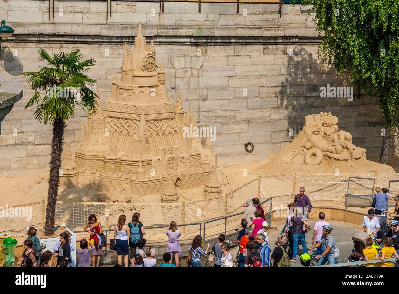 People admiring the huge sand sculpture of a castle with Mickey Mouse ...