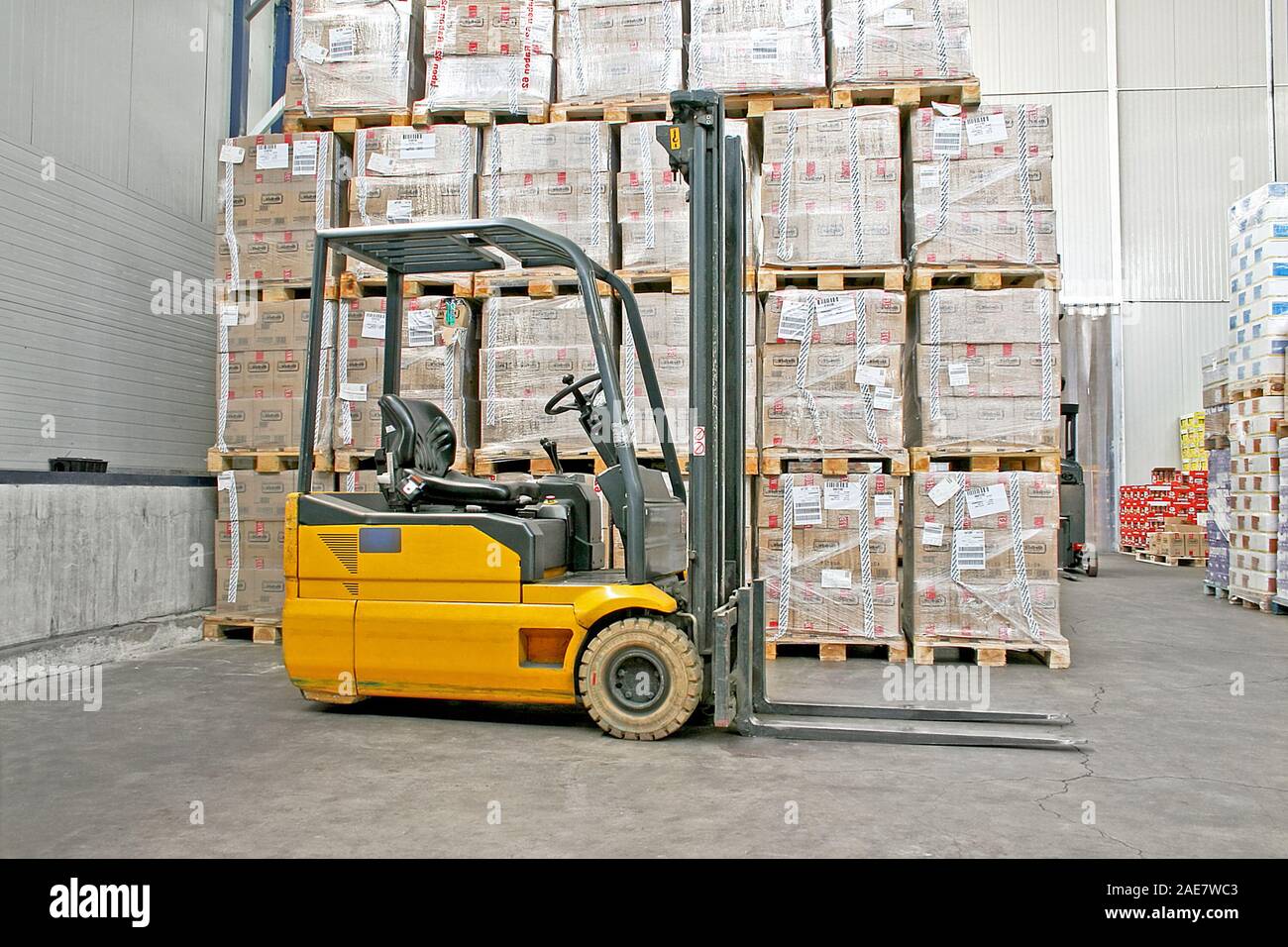 Yellow fork lifter truck and cargo boxes Stock Photo - Alamy